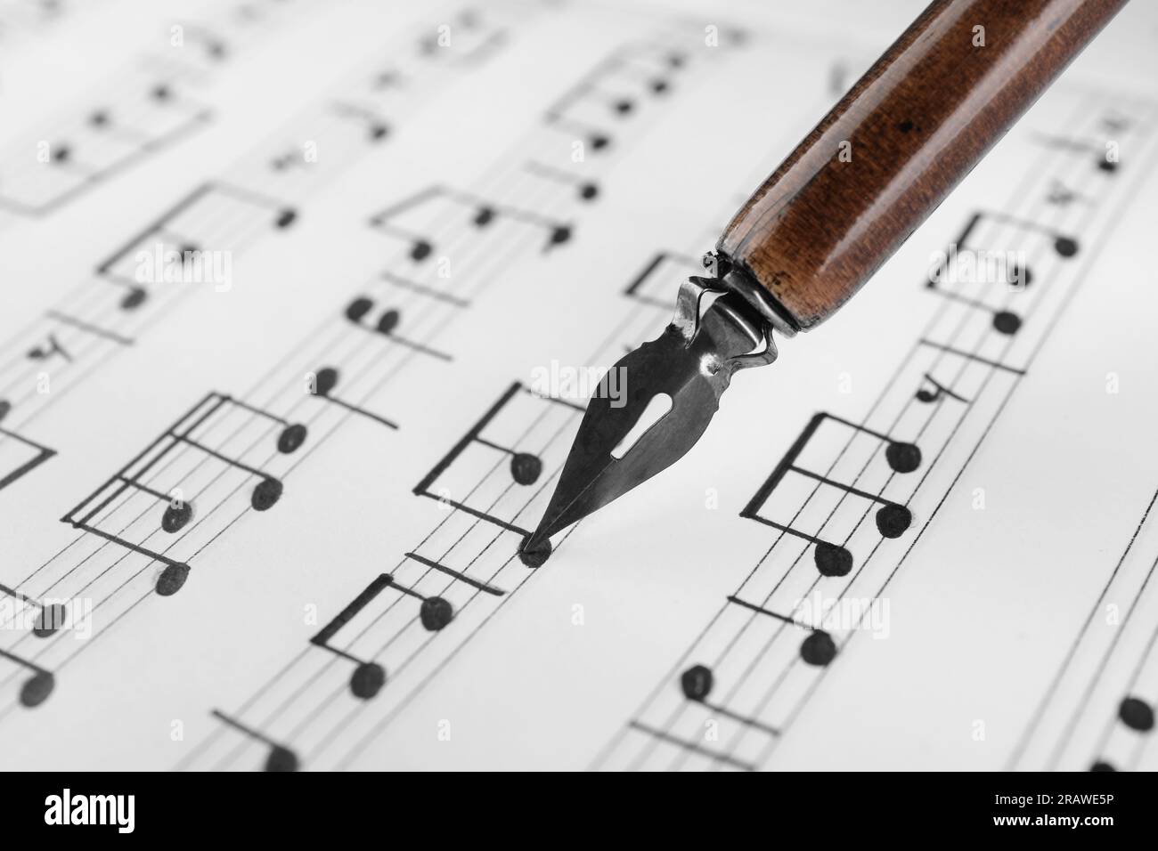 Writing musical notes with fountain pen on sheet of paper, closeup view ...