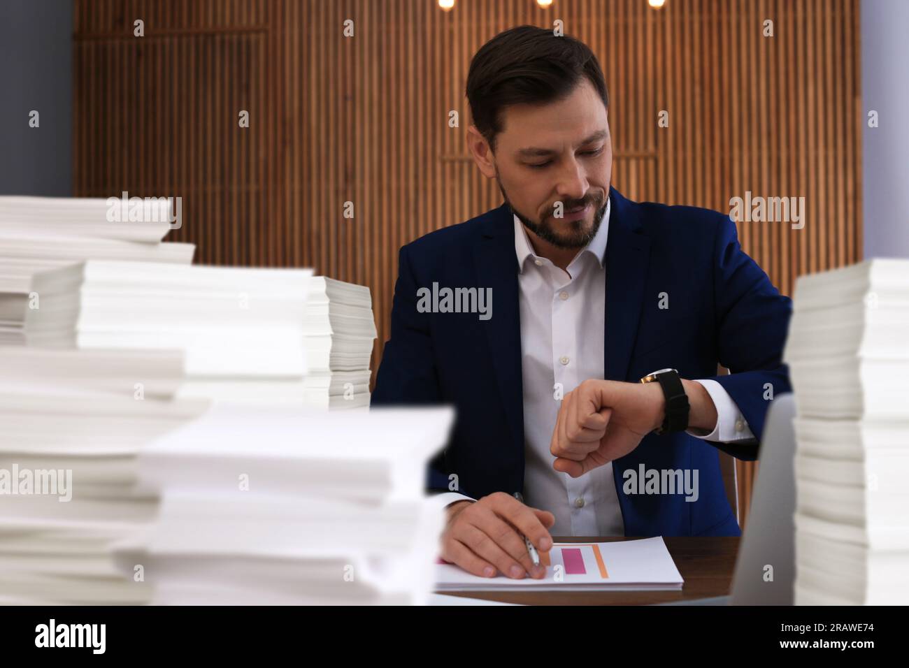 Deadline concept. Busy man looking at wristwatch in office. His ...