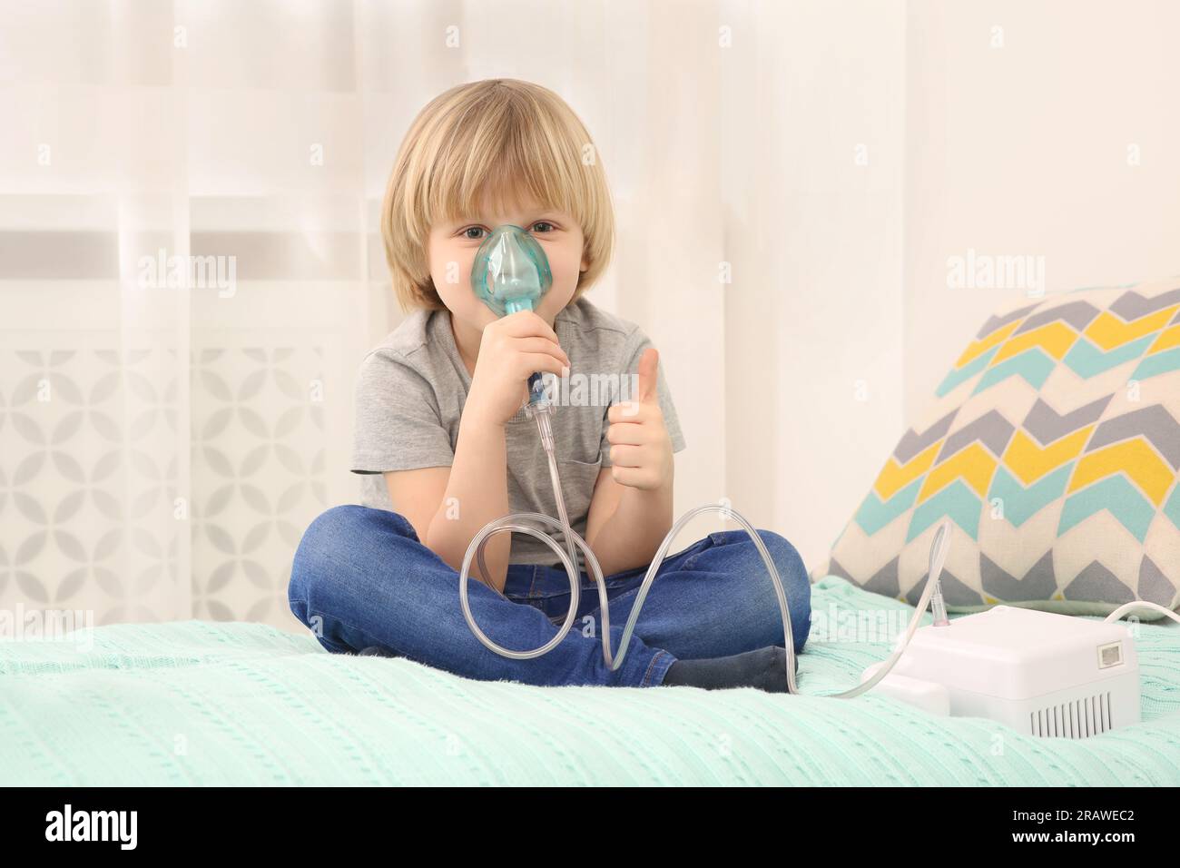 Sick little boy using nebulizer for inhalation on bed at home Stock ...