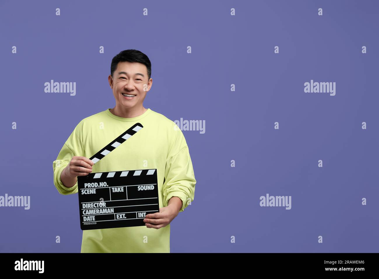 Happy asian actor with clapperboard on purple background, space for ...