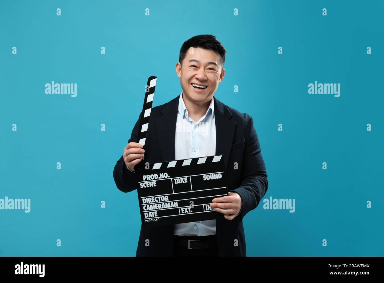 Happy asian actor with clapperboard on light blue background. Film ...