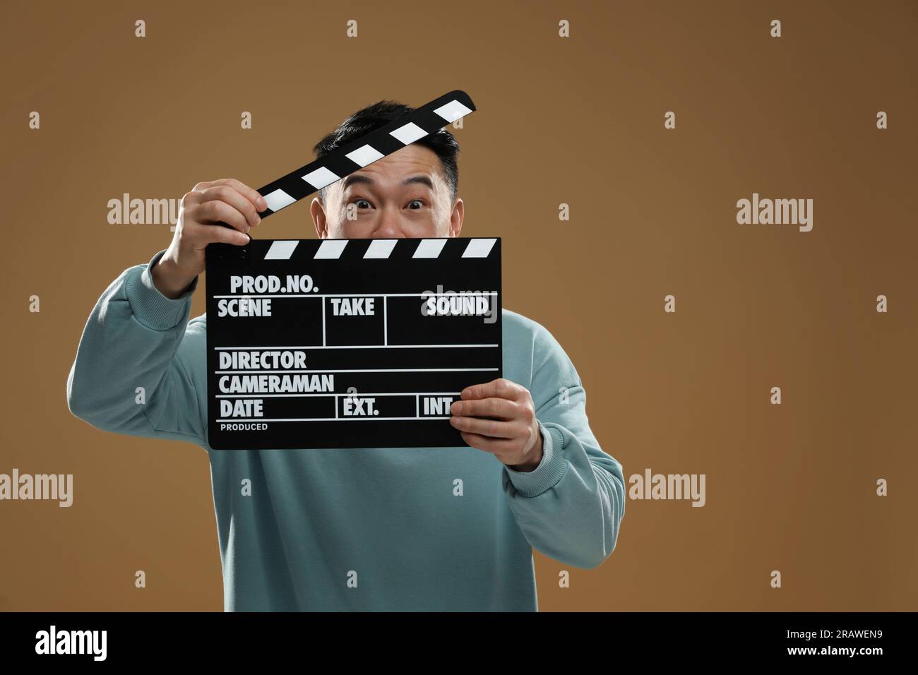Emotional asian actor with clapperboard on brown background, space for ...