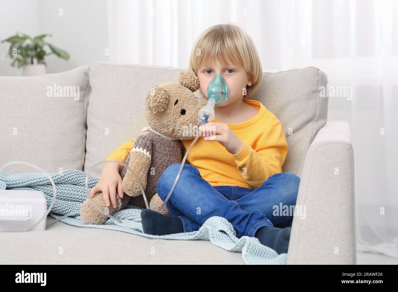 Boy with toy bear using nebulizer for inhalation at home Stock Photo ...
