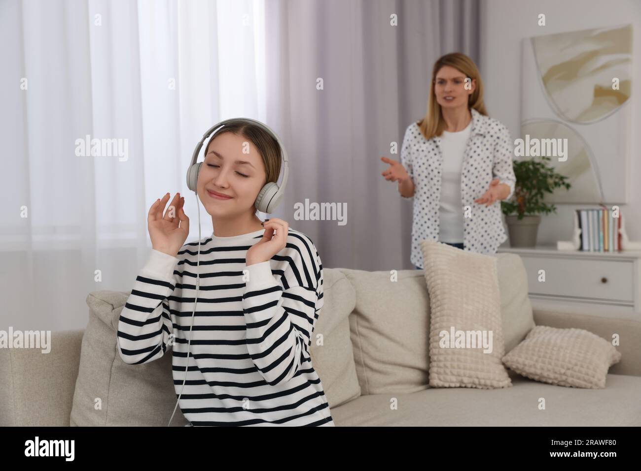 Teenage daughter with headphones ignoring her mother at home Stock Photo - Alamy