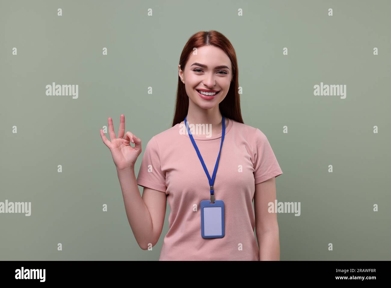 Happy woman with VIP pass badge showing OK gesture on pale green ...