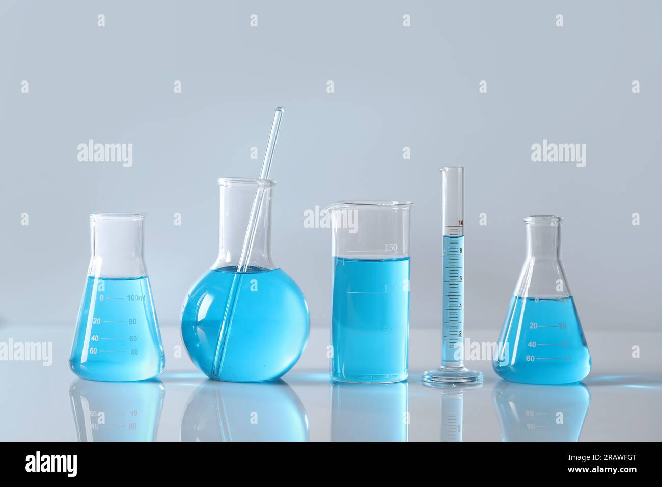 Different laboratory glassware with light blue liquid on table Stock ...