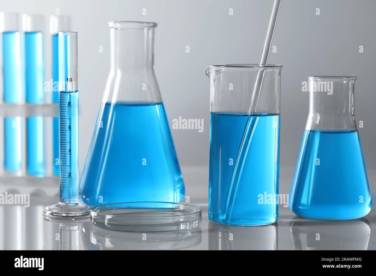 Different laboratory glassware and test tubes with light blue liquid on ...