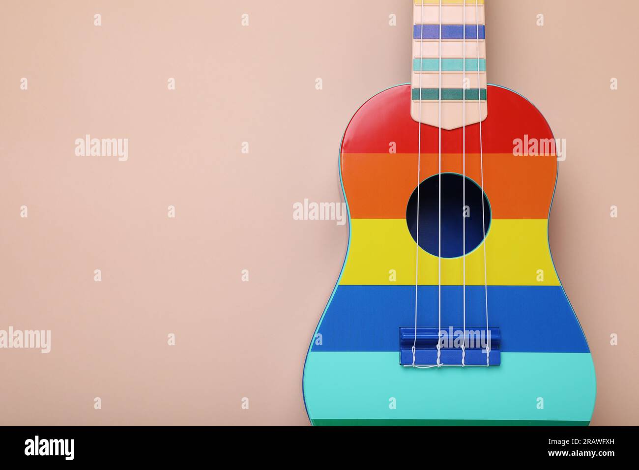 Colorful ukulele on beige background, top view and space for text ...