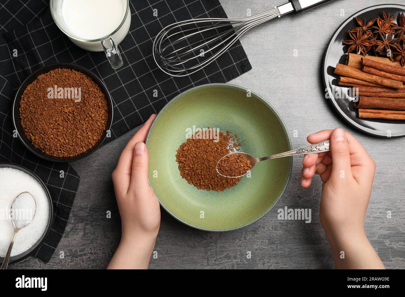 Making dalgona coffee. Woman pouring instant granules into bowl at gray ...