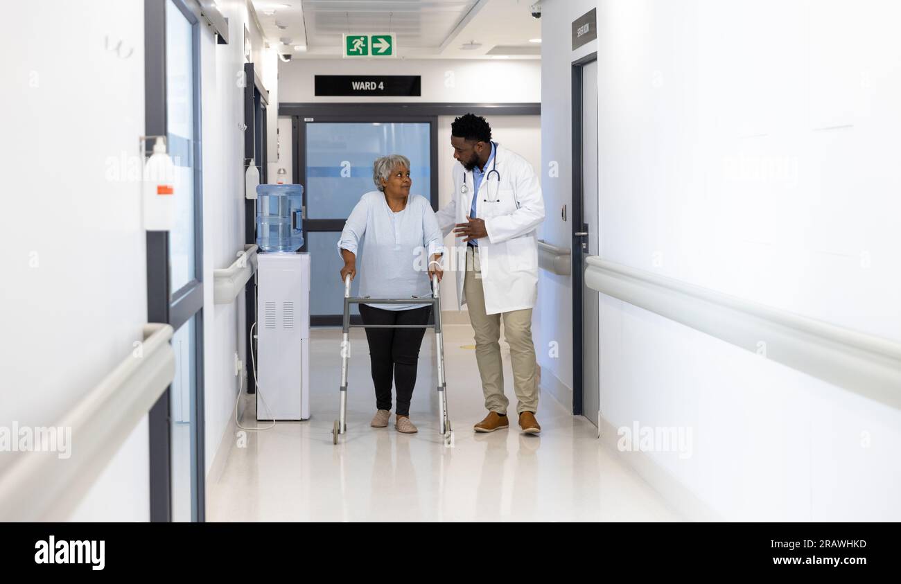 Diverse male doctor and senior female patient with walking frame ...