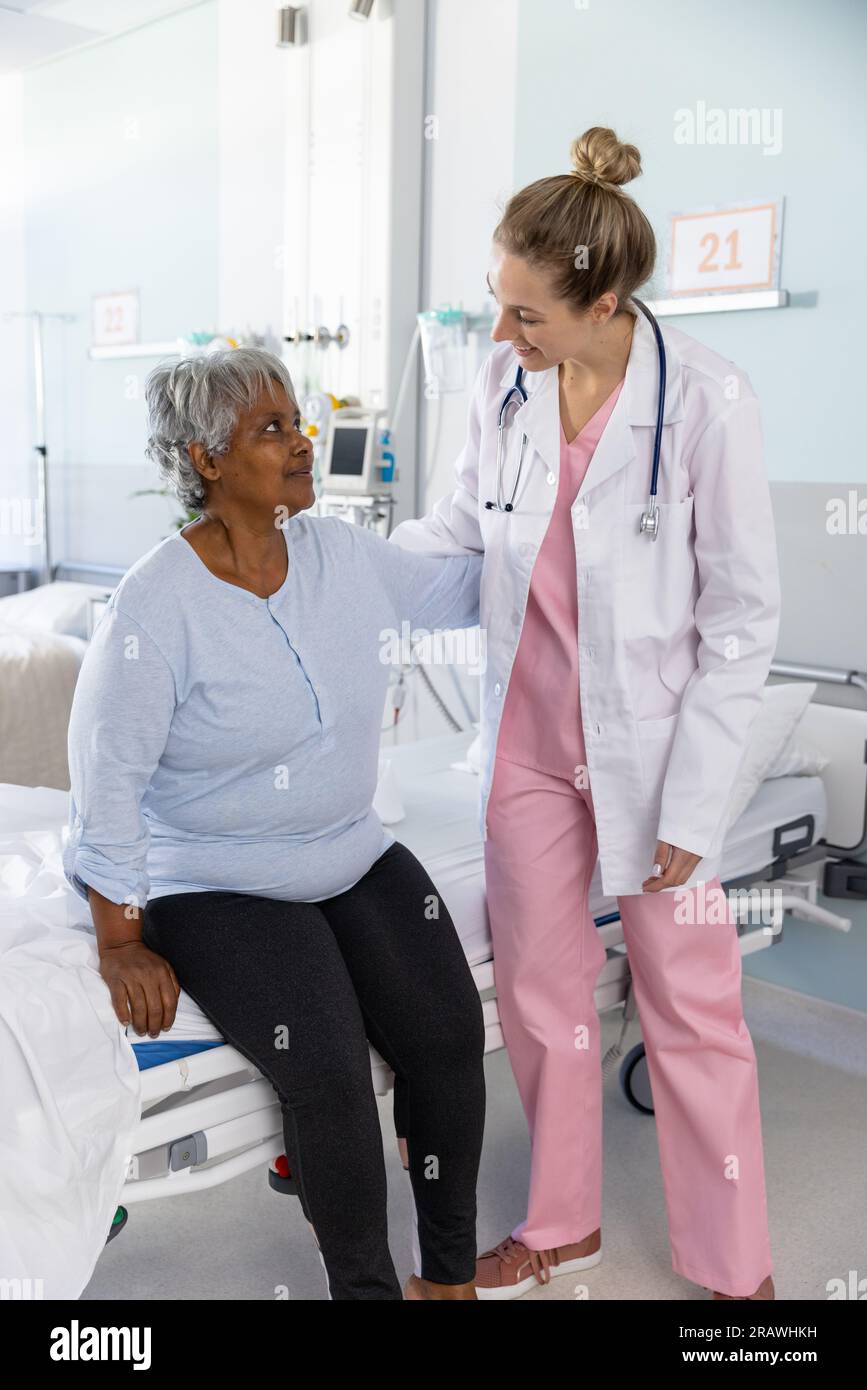 Diverse female doctor and senior female patient embracing and talking ...