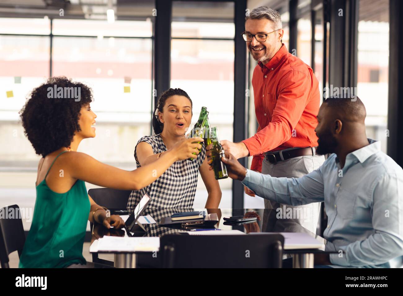 Happy diverse casual business colleagues making a toast with bottles of ...