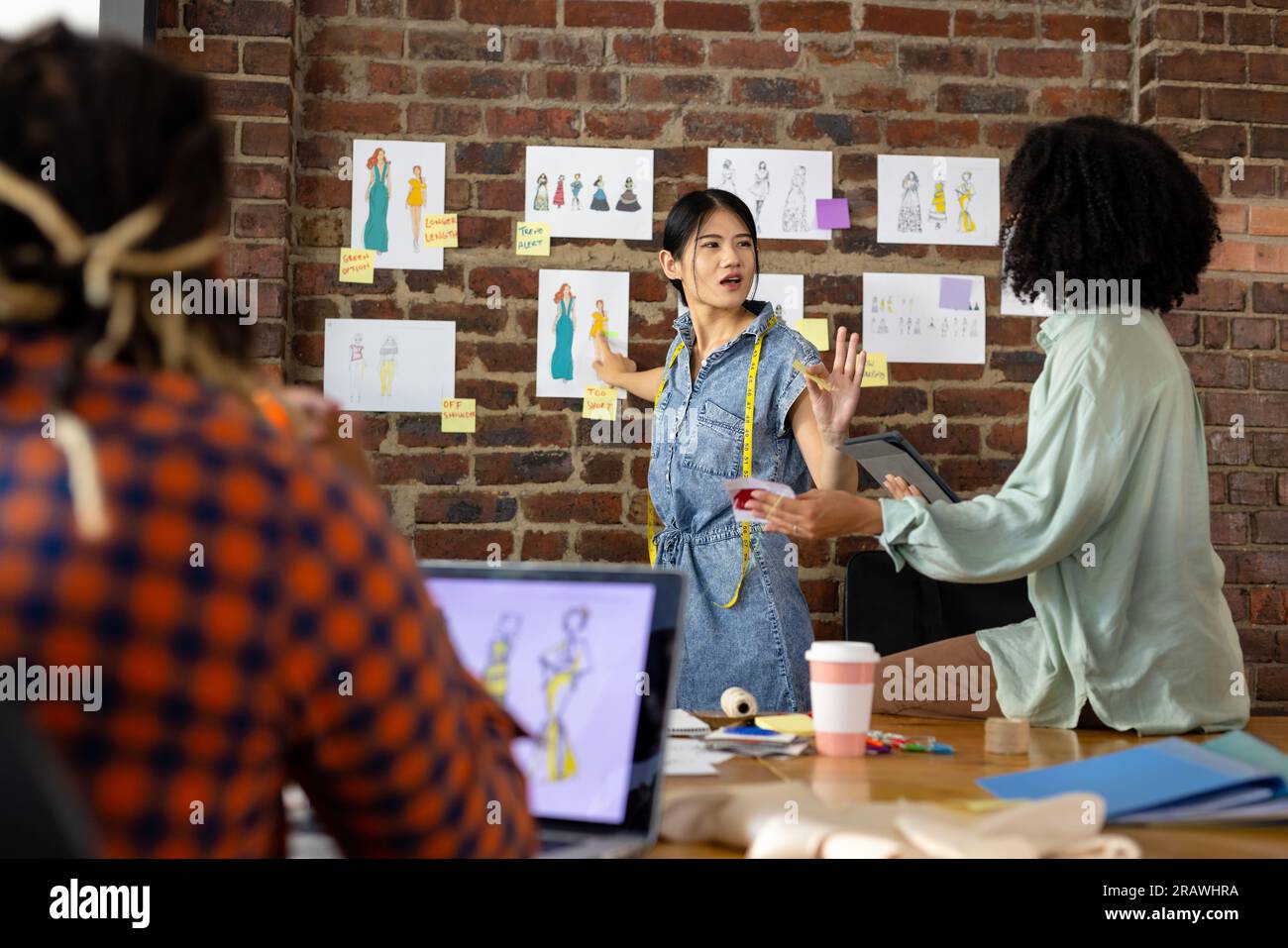 Happy diverse fashion designers using laptop and discussing designs in ...