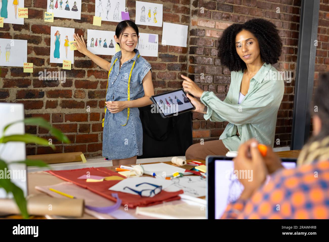 Happy diverse fashion designers using tablet, discussing designs in ...