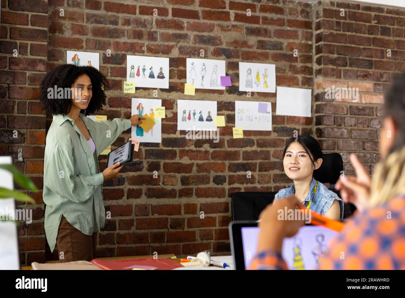 Happy diverse fashion designers using tablet and laptop, discussing ...