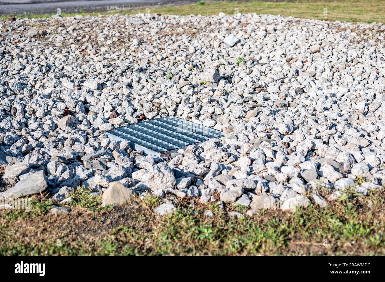 Grated storm drain inlet surrounded by rock for soil erosion control ...