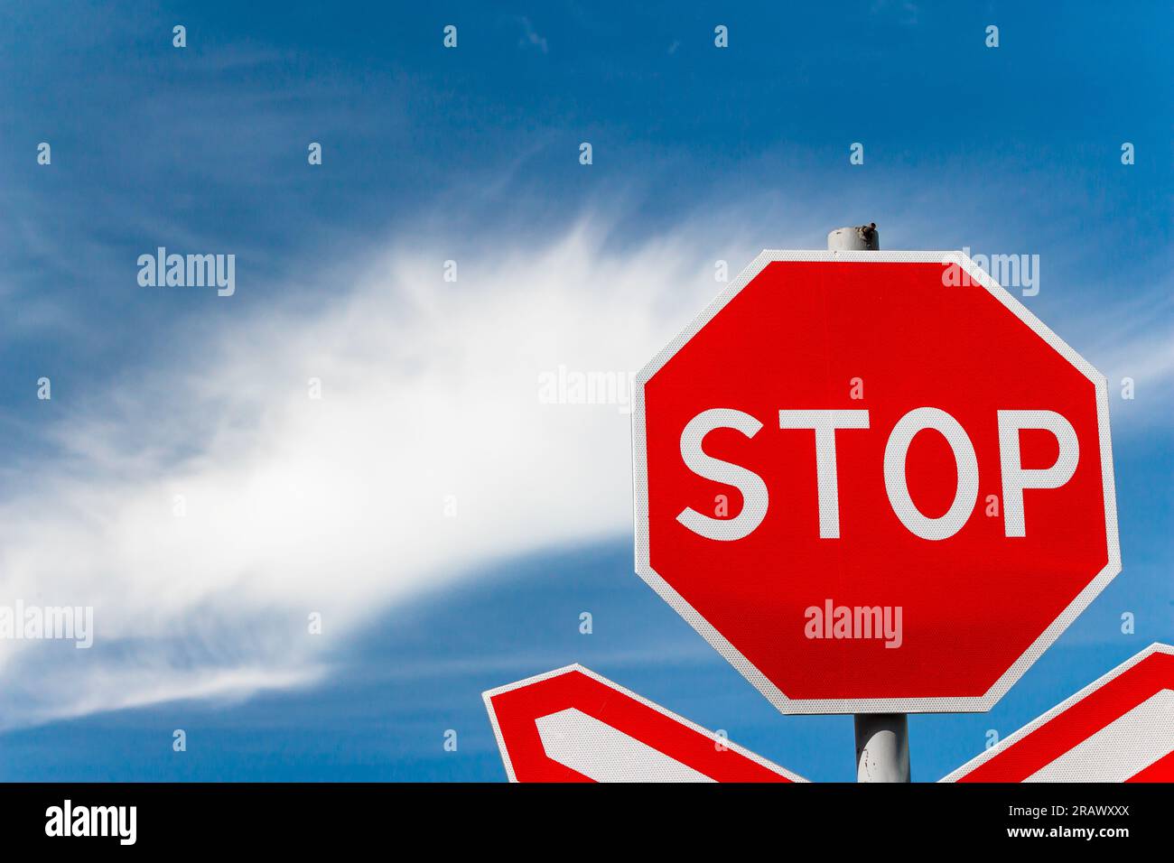 Bright red STOP sign on the road in front of the railway crossing Stock ...