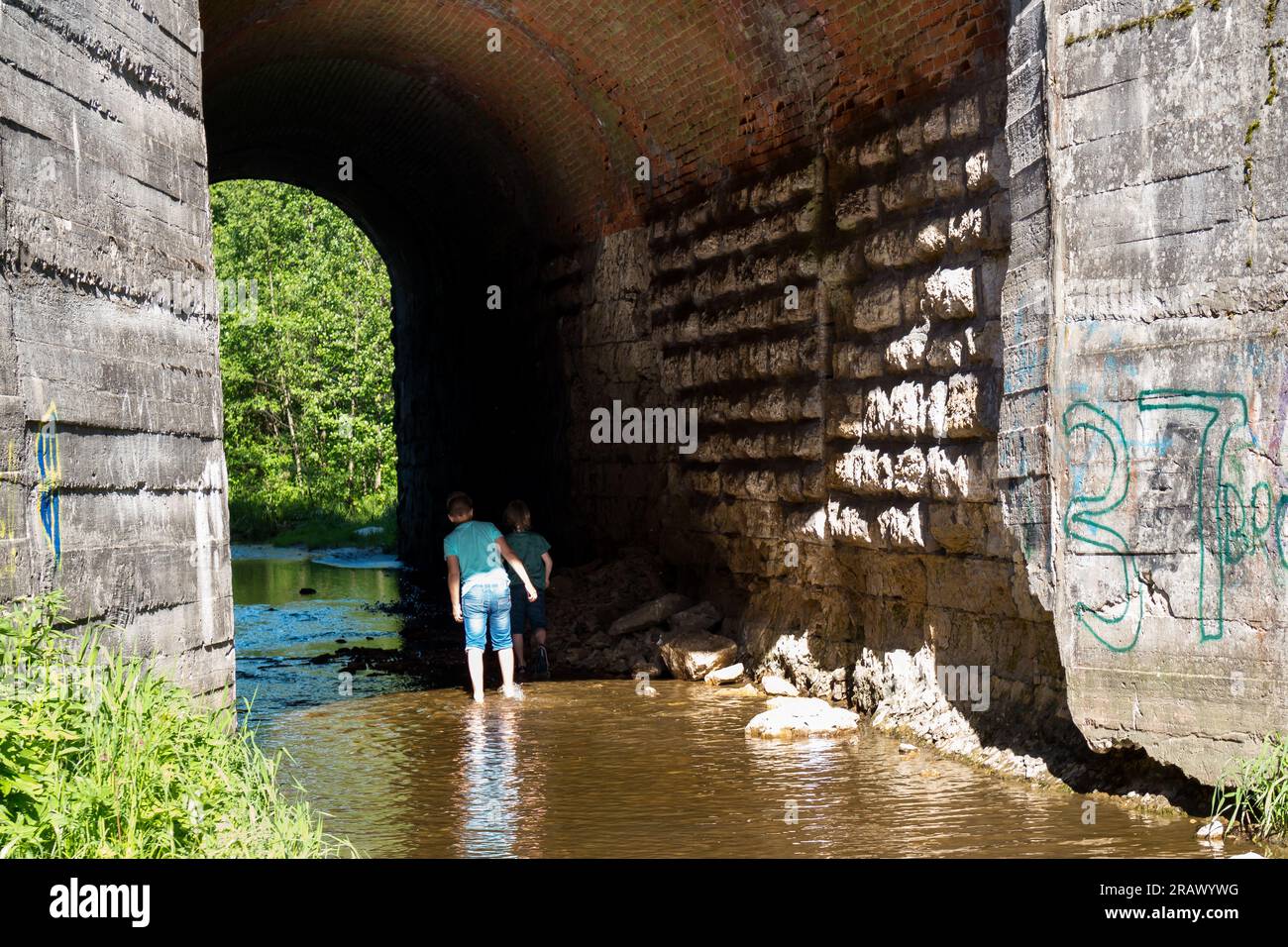 Children go through an old tunnel with a stream Stock Photo - Alamy