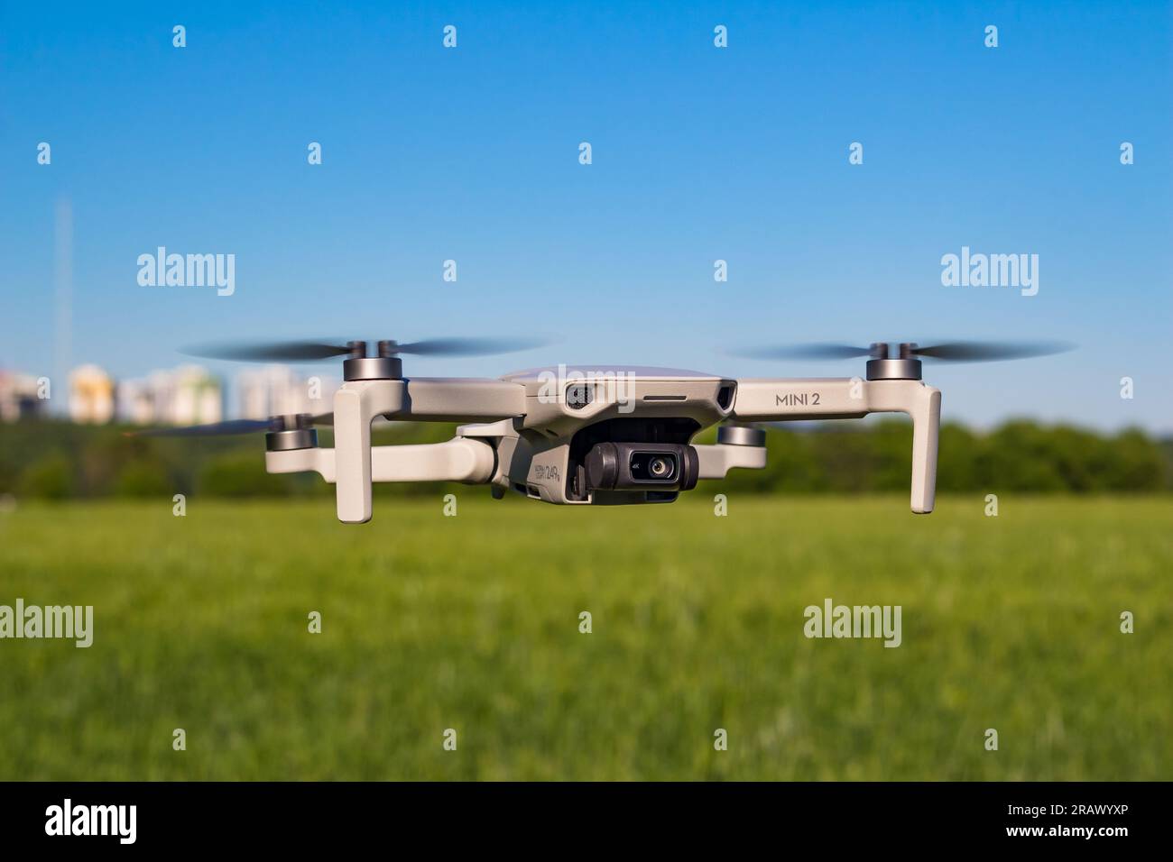 DJI Mini 2 drone in flight with fields and houses in the background ...