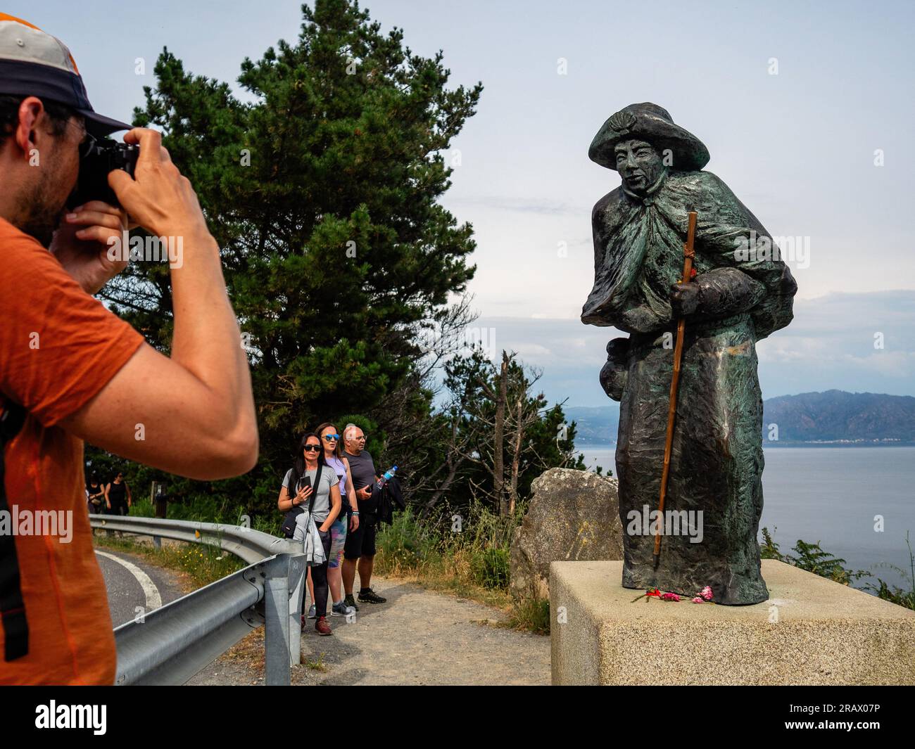 A hiker is seen taking a photo of the sculpture of an Asian pilgrim ...