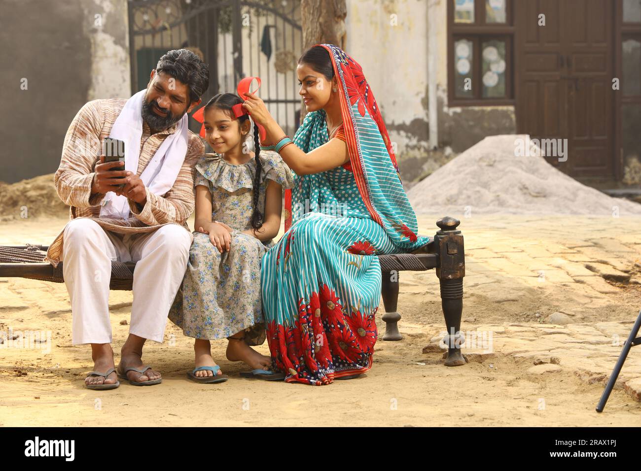 Happy rural Indian family sitting together outside their cottage in day ...