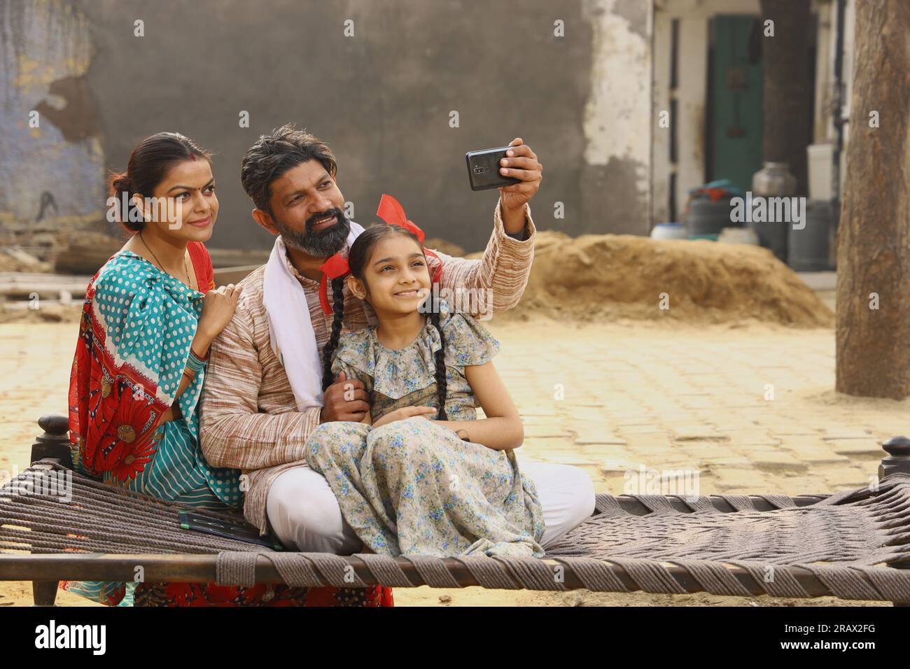 Happy rural Indian family sitting together outside their cottage in day ...