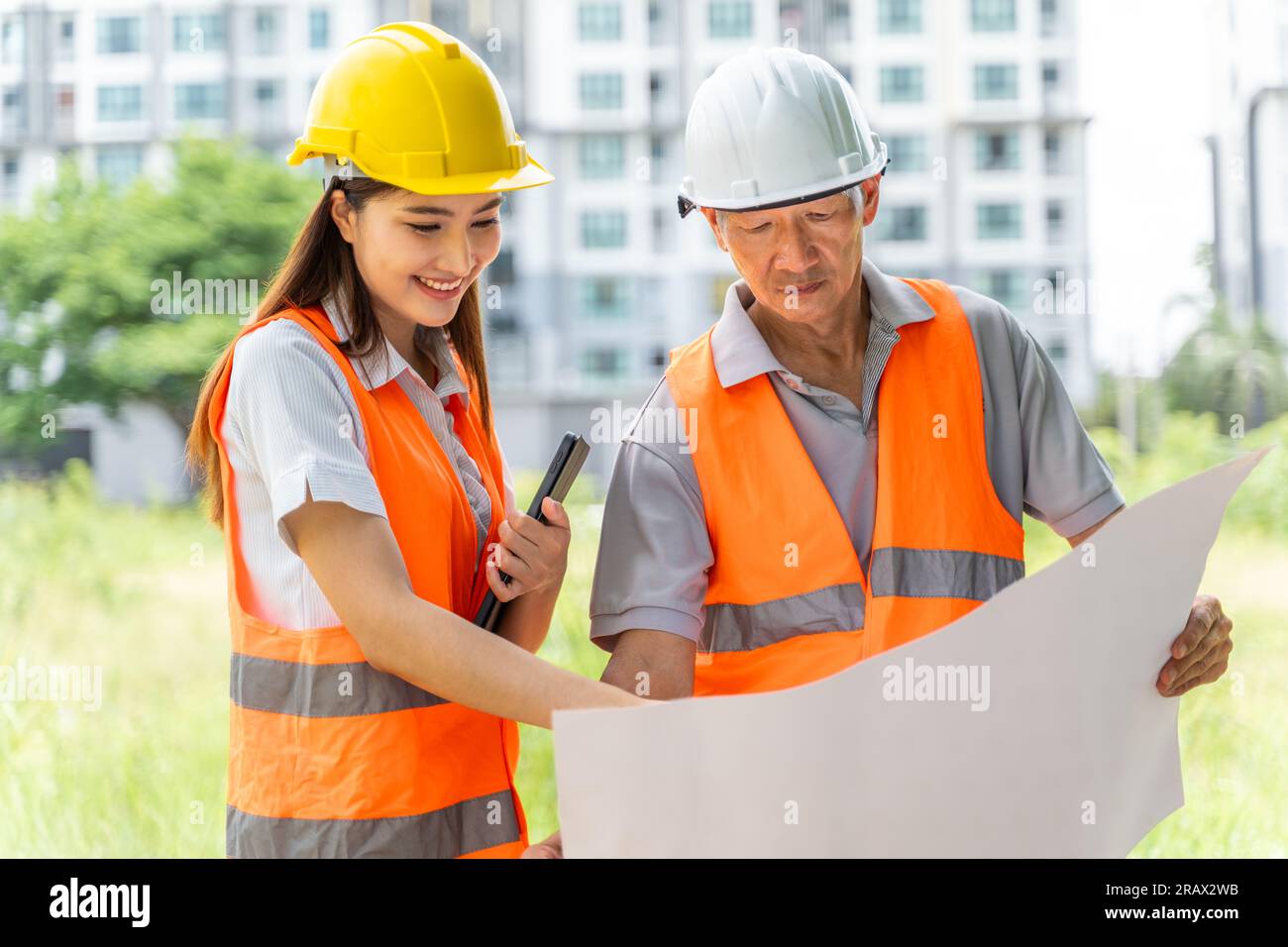 Serious male and happy female engineers in yellow and white hardhat ...
