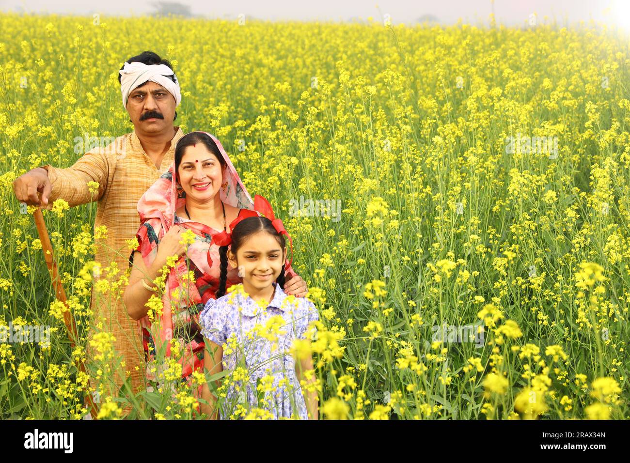 Happy rural Indian family standing in a mustard field and enjoying the ...