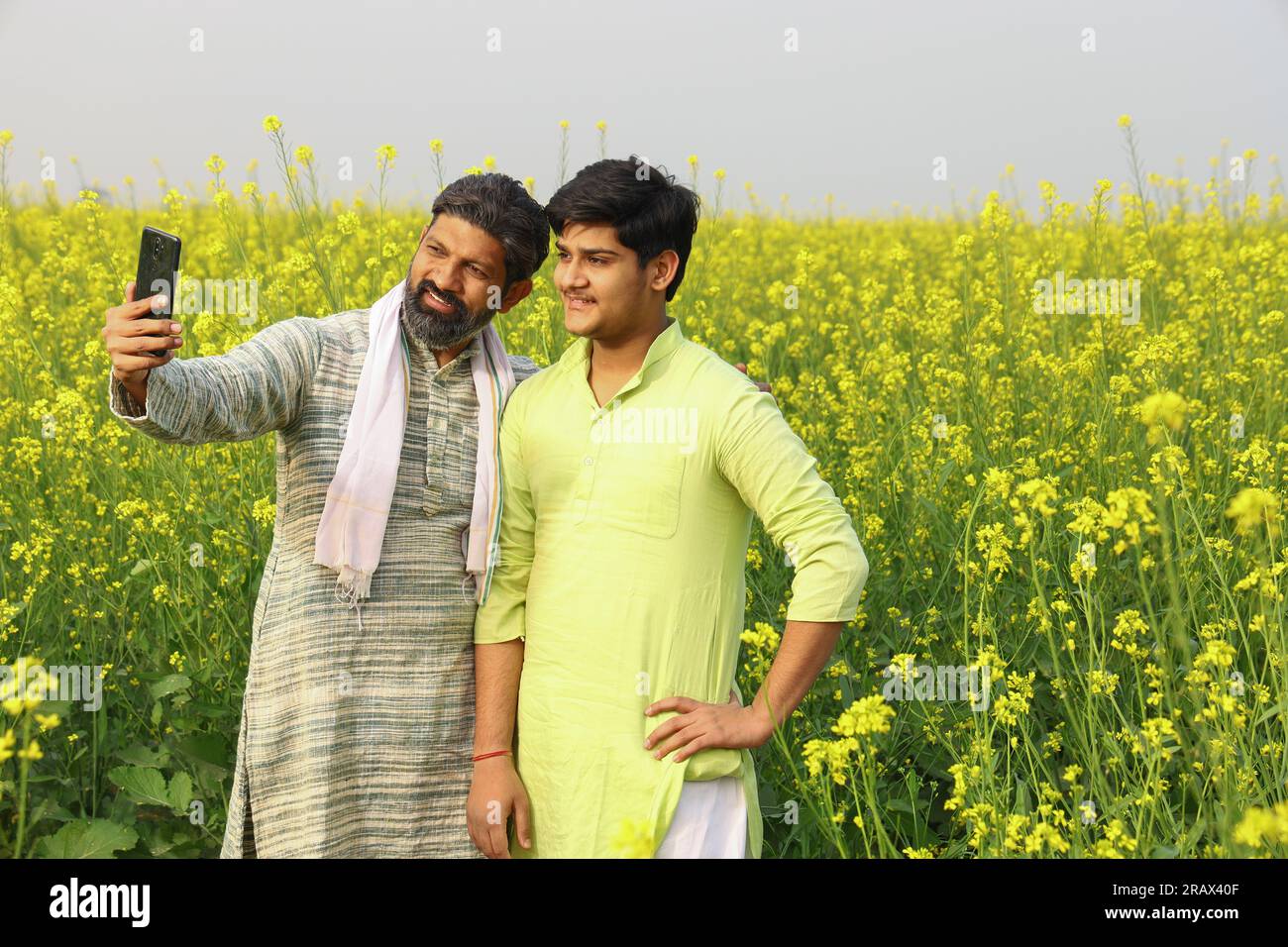 Happy rural Indian men standing in a mustard field taking a selfie from ...