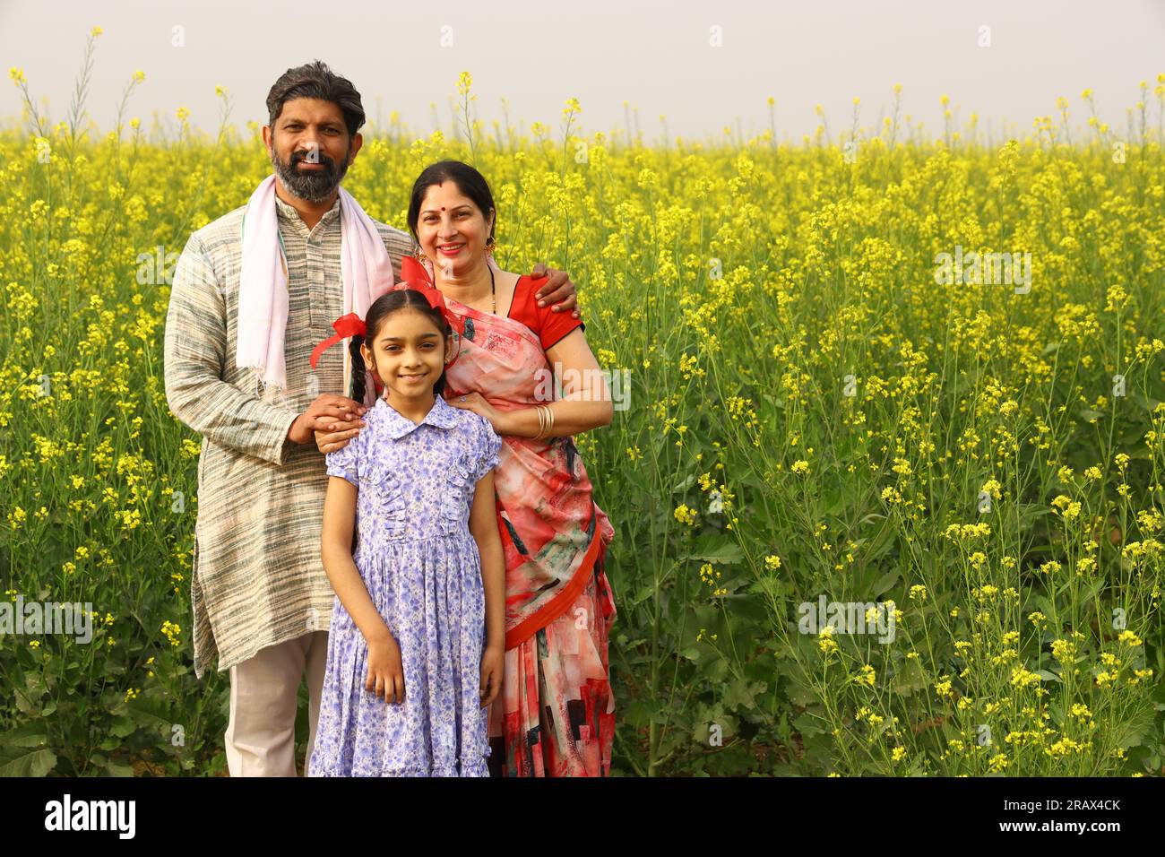 Happy rural Indian family standing in a mustard field and enjoying the ...