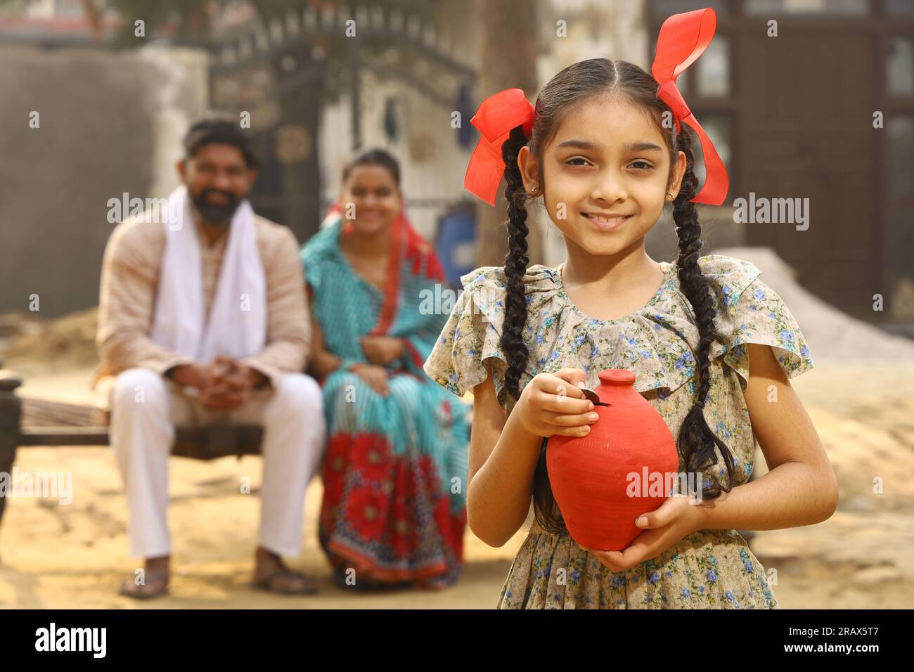 Happy rural Indian family sitting together, daughter is holding a piggy ...