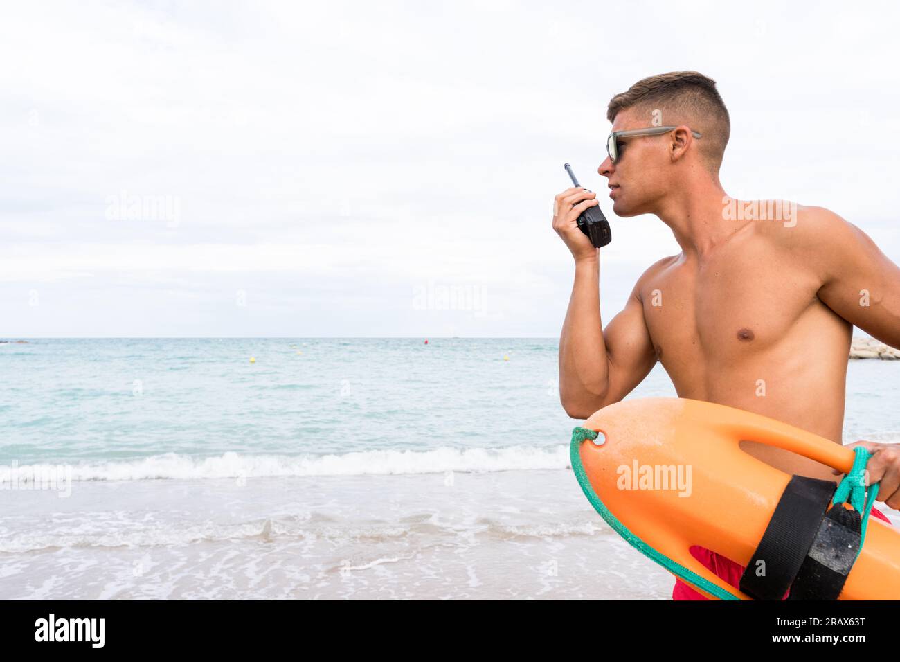 Photo with copy space of a handsome Lifeguard using the radio while ...