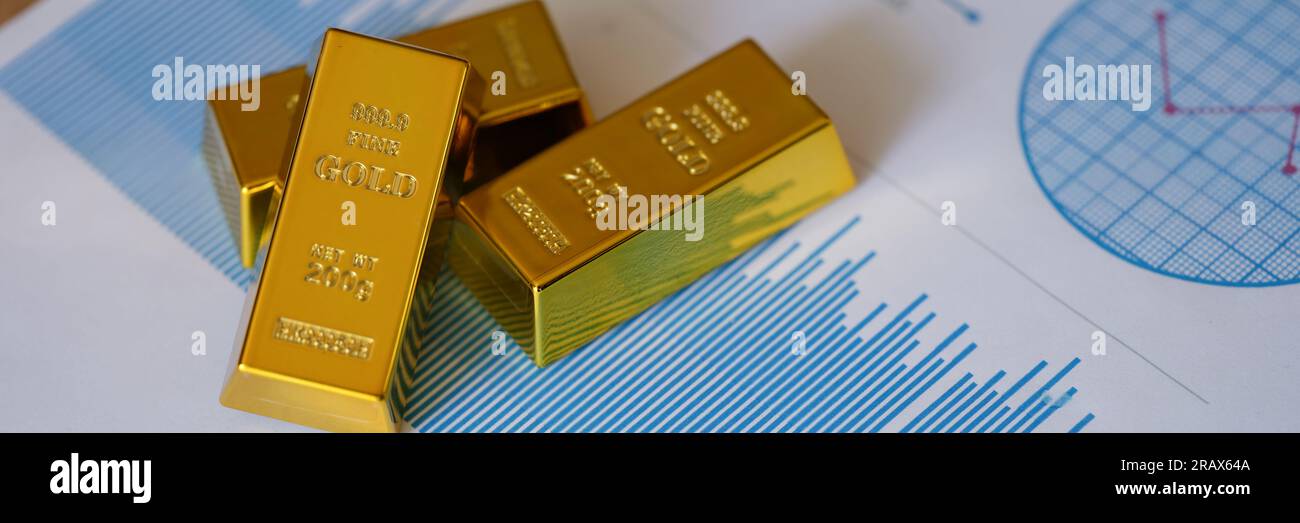 Small gold ingots on financial statistics document with charts and ...