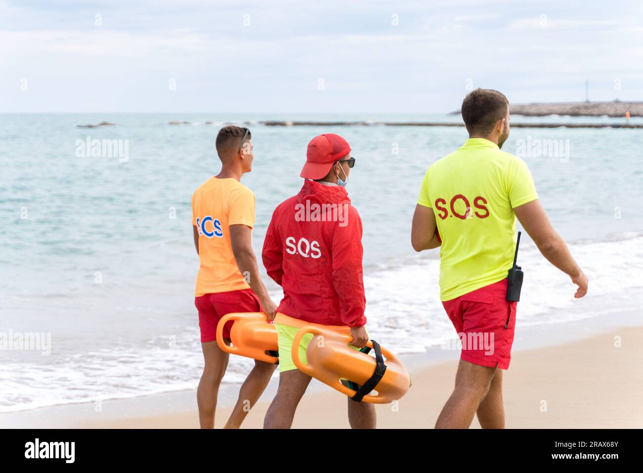 Rear view of three members of a team of Lifeguards on duty on a beach ...