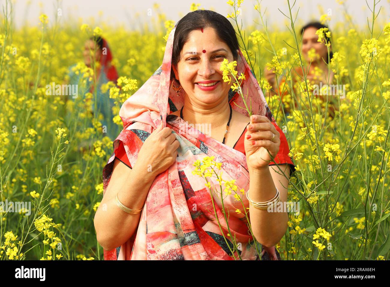 Happy rural Indian women standing in a mustard field enjoying the ...