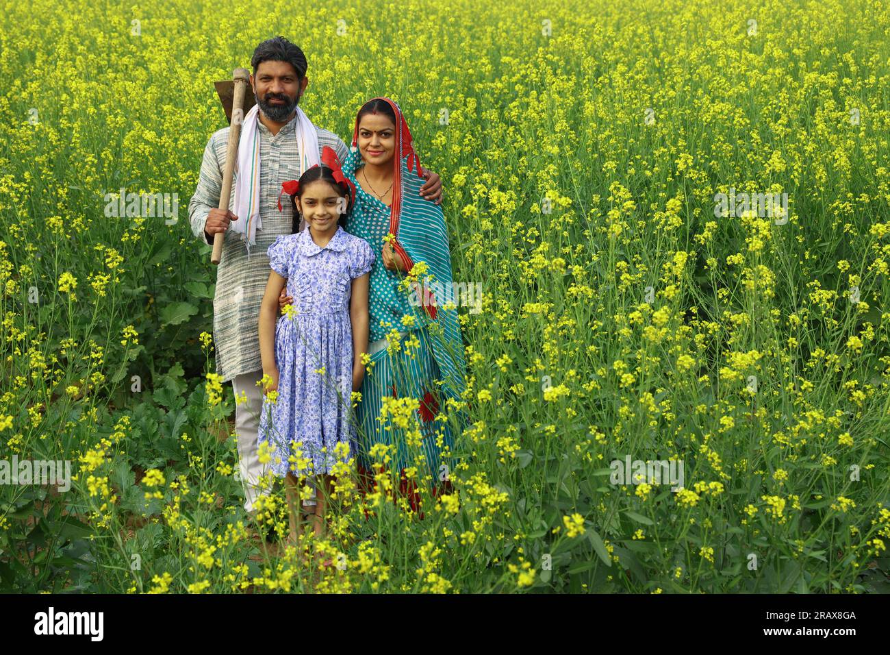 Happy rural Indian family standing in a mustard field and enjoying the ...