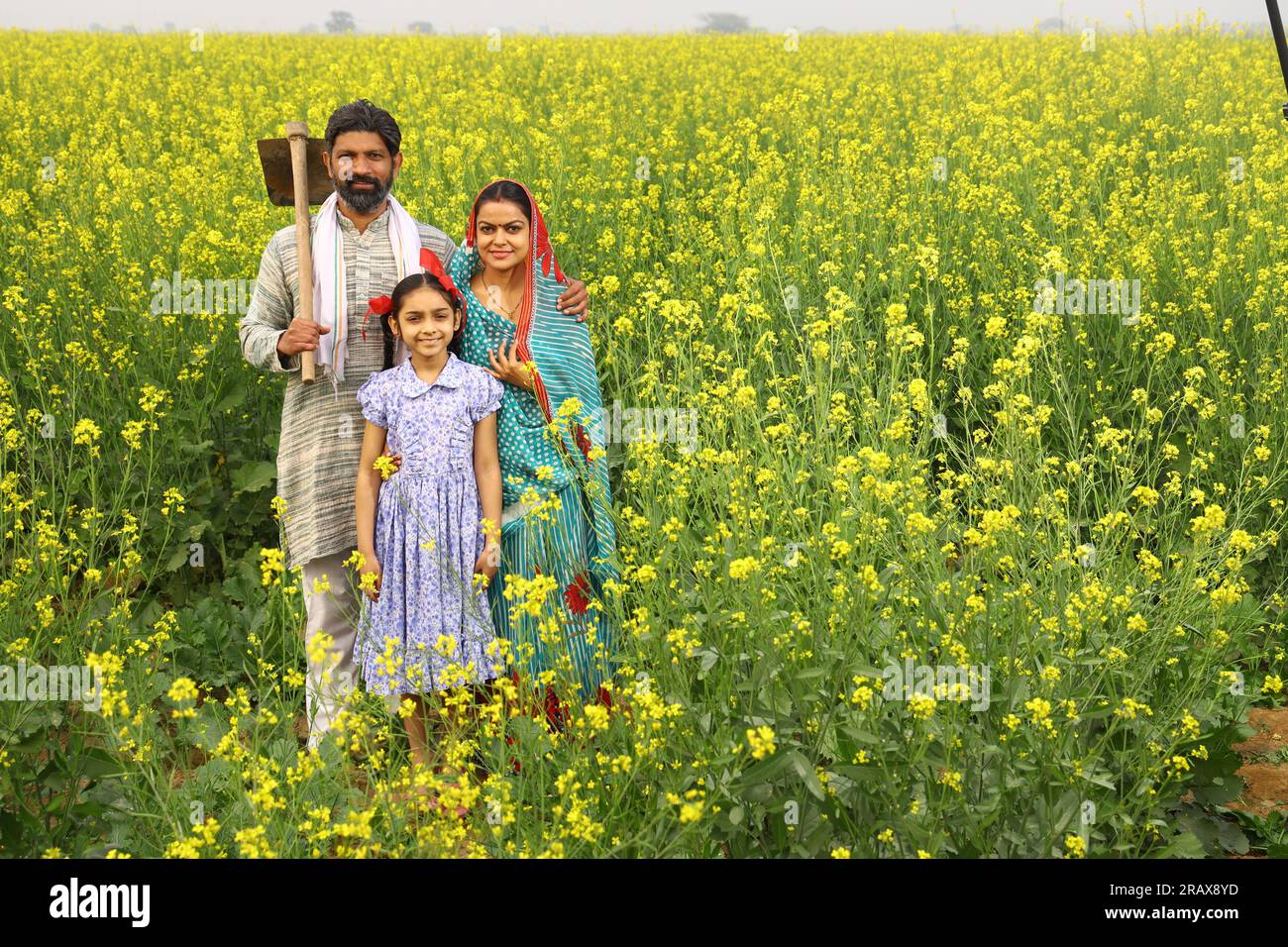 Happy rural Indian family standing in a mustard field and enjoying the ...
