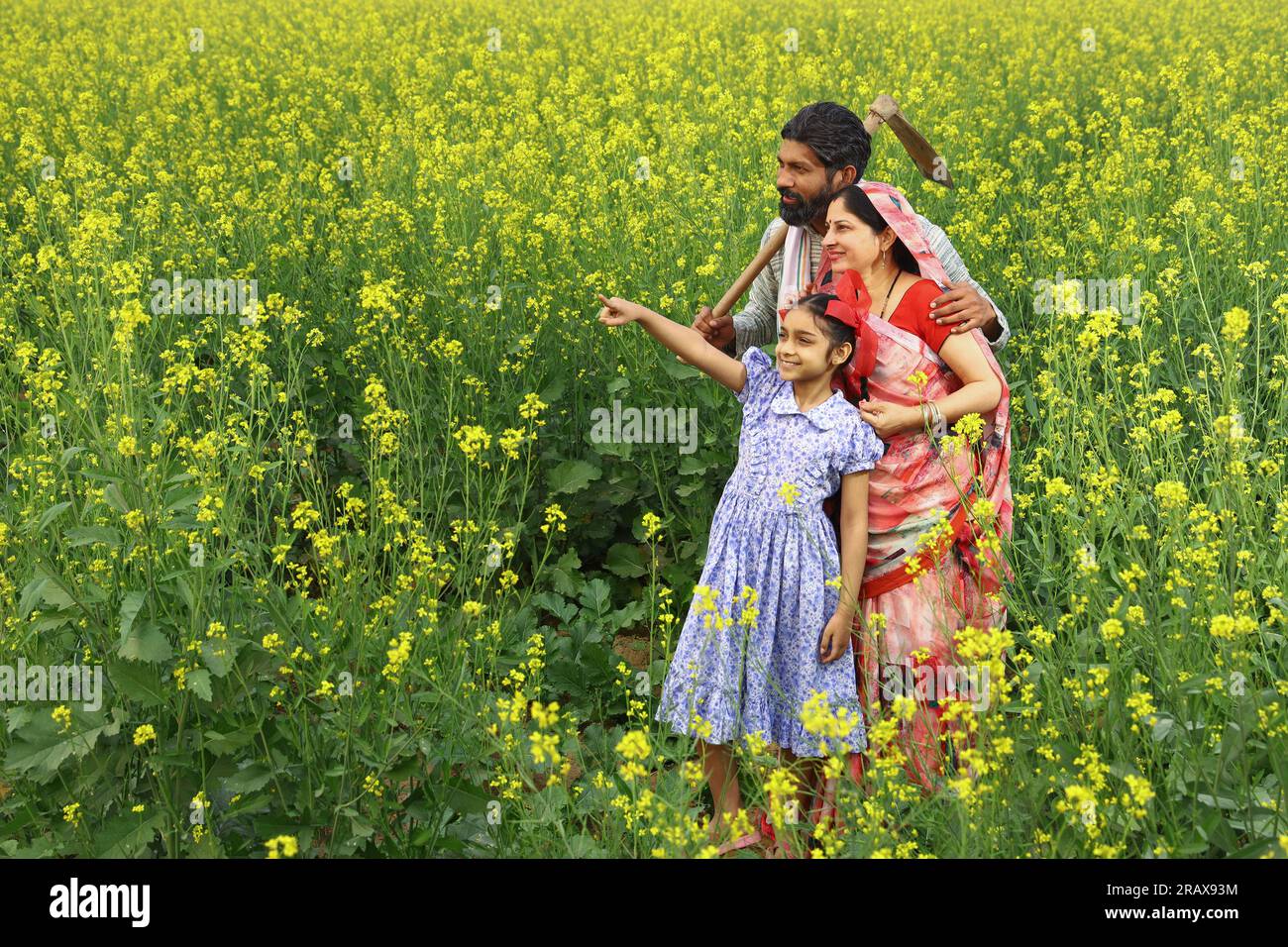 Happy rural Indian family standing in a mustard field and enjoying the ...