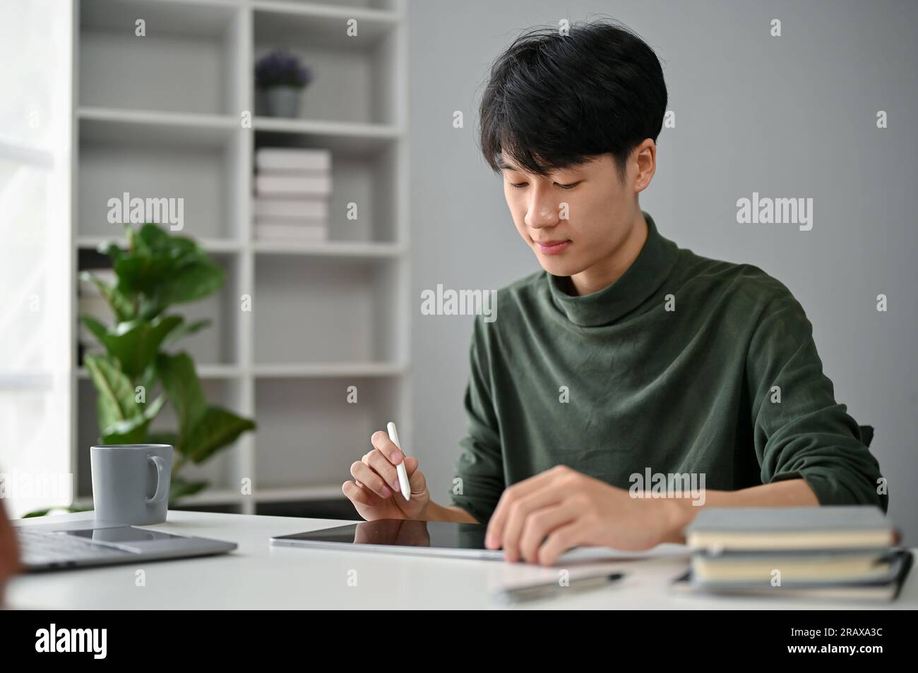 A concentrated and smart young Asian man in casual clothes using his ...