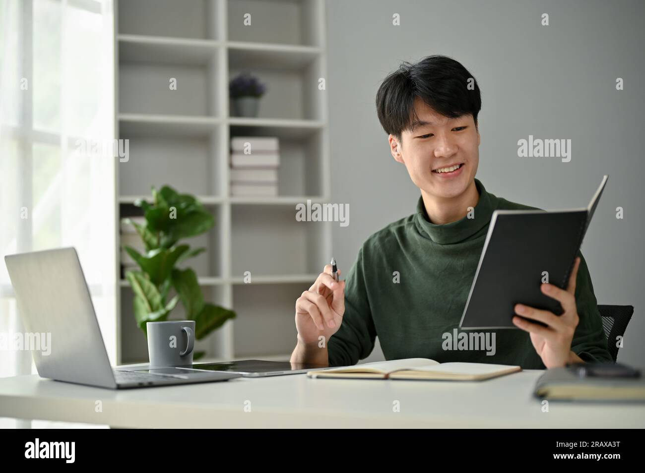 A happy young Asian man in casual clothes checks his meeting schedules ...