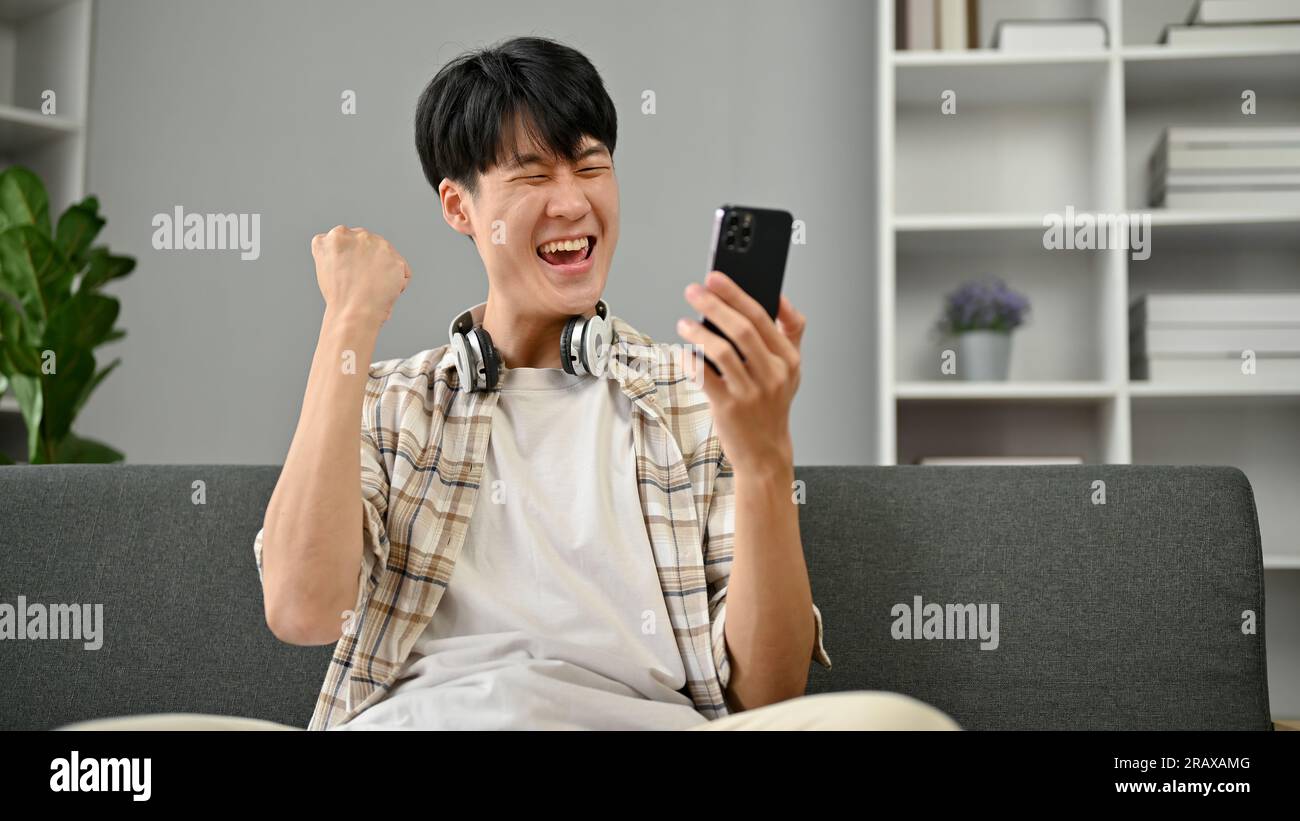 An overjoyed young Asian man in casual clothes looking at his ...