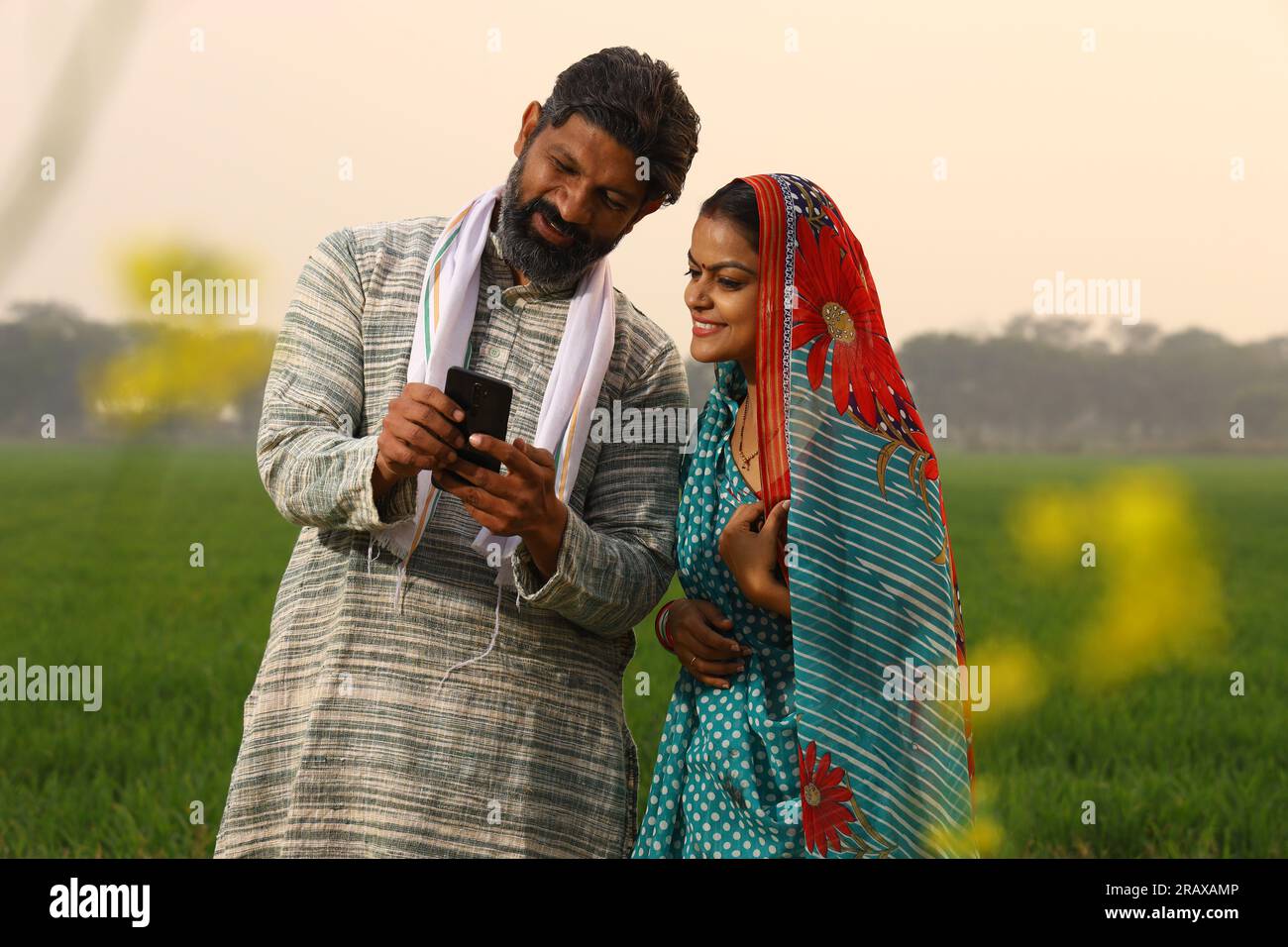 Happy rural Indian villager family standing in a mustard field husband ...