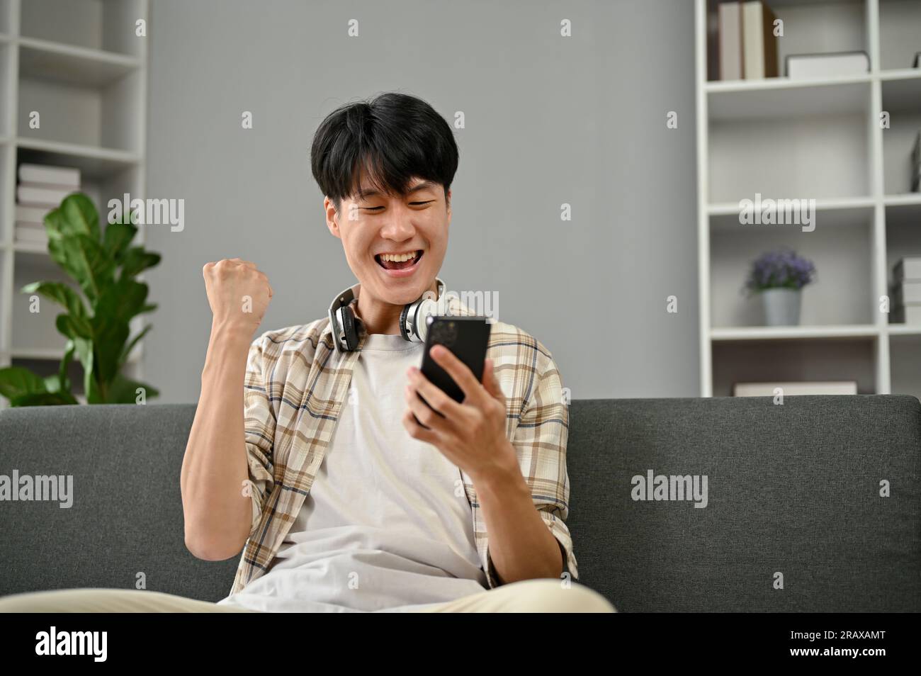 A happy and smiling young Asian man in casual clothes looking at his ...