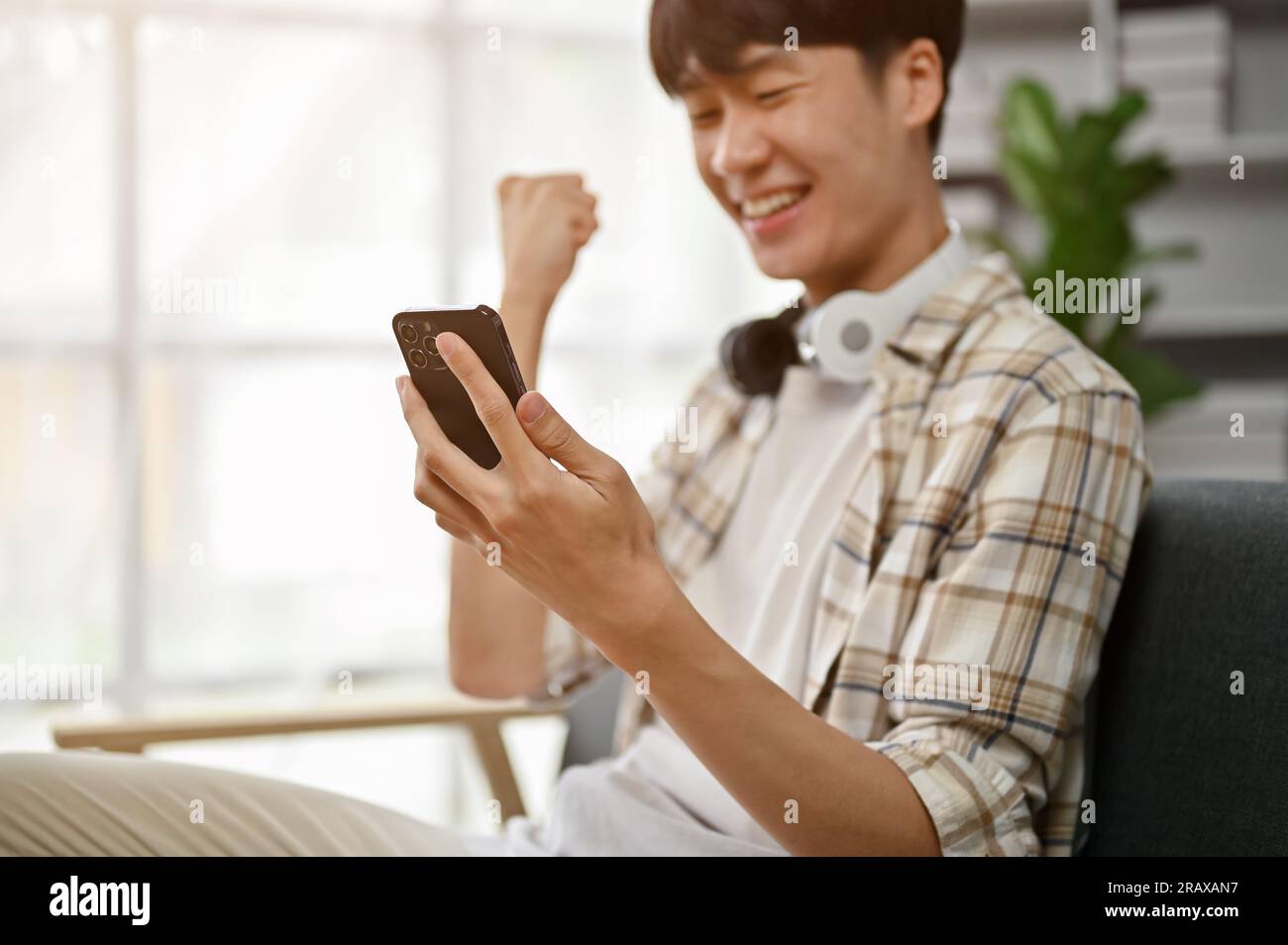 Close-up image of a overjoyed and happy young Asian man looking down at ...