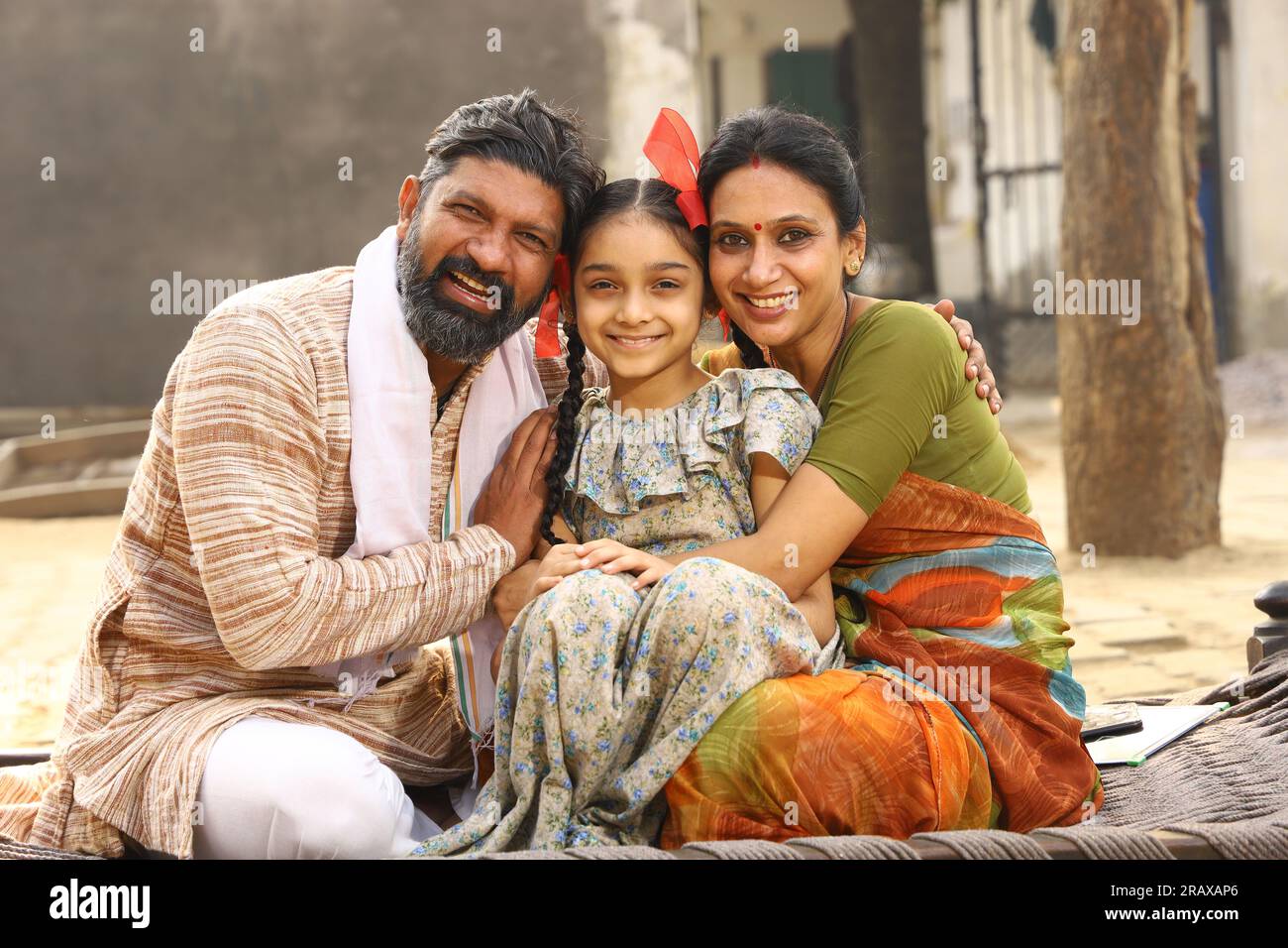 Happy rural Indian family sitting together outside their cottage in day ...