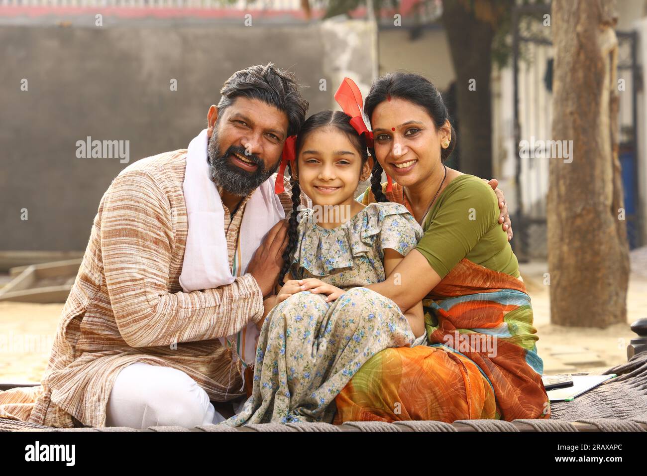 Happy rural Indian family sitting together outside their cottage in day ...