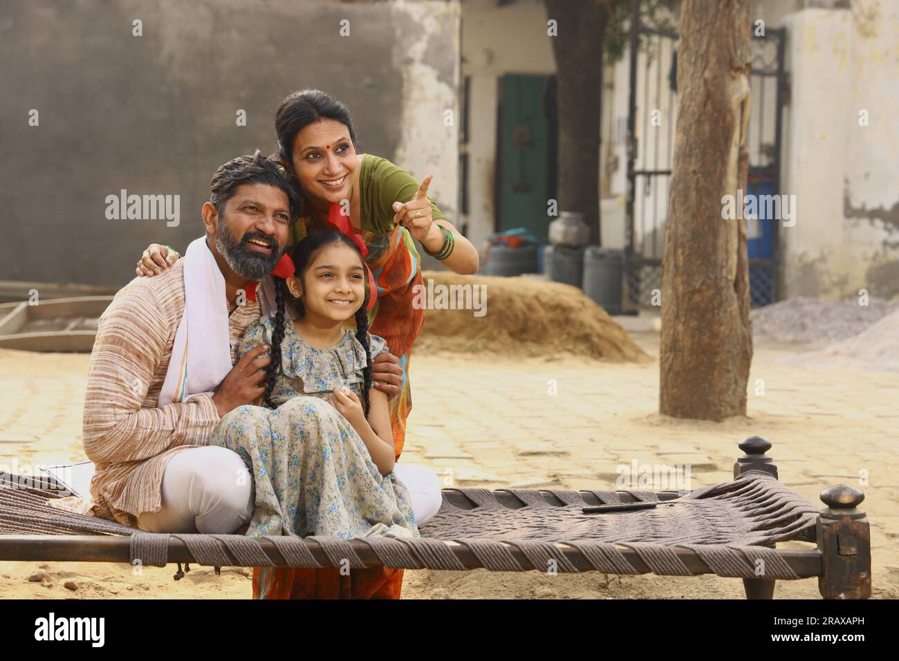 Happy rural Indian family sitting together outside their cottage in day ...