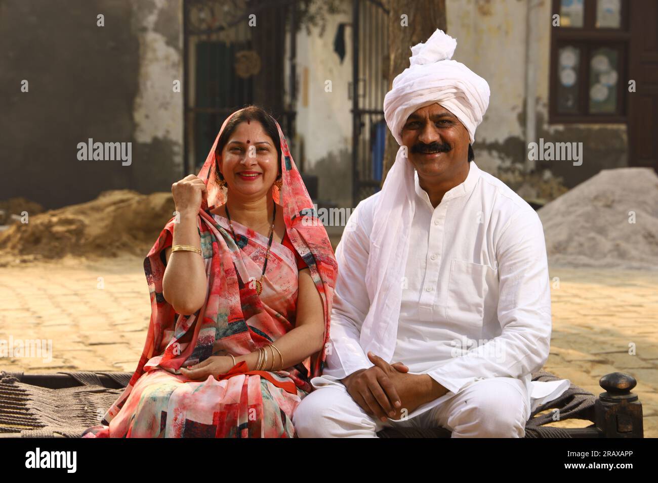 Happy Indian Rural family in village. Husband and wife sitting on cot ...