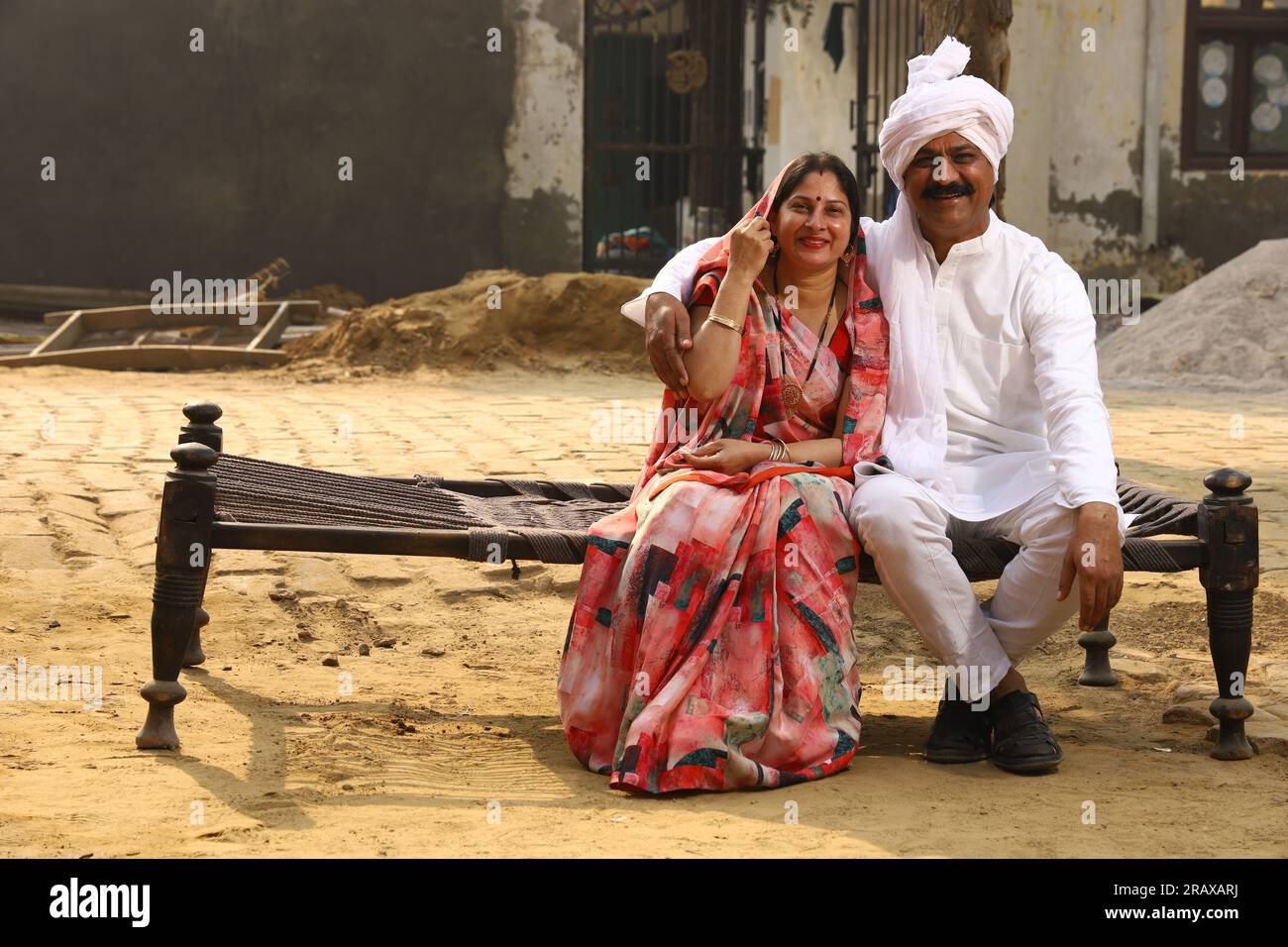 Happy Indian Rural family in village. Husband and wife sitting on cot ...