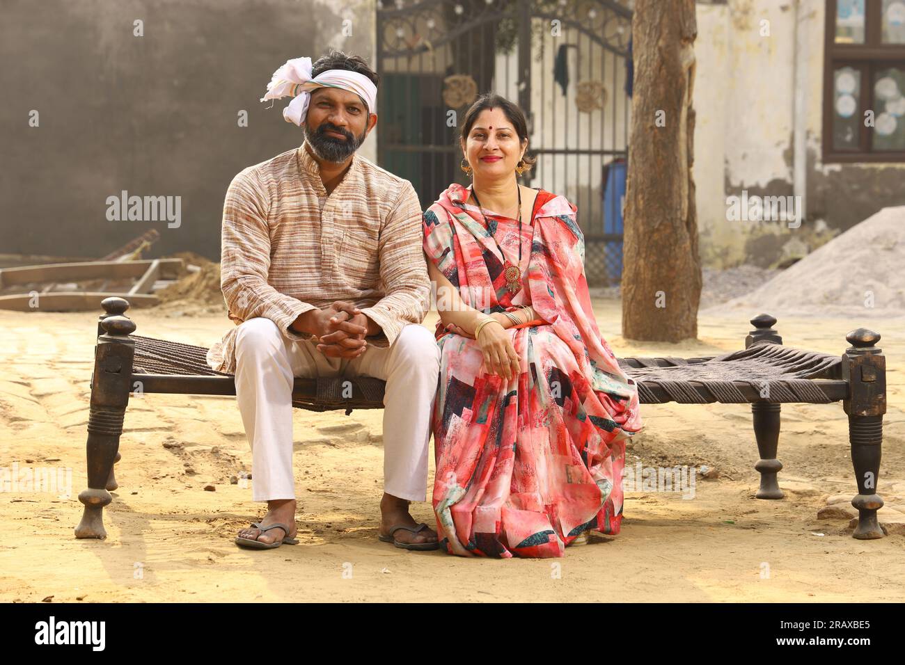 Happy Indian Rural family in village. Husband and wife sitting on cot ...